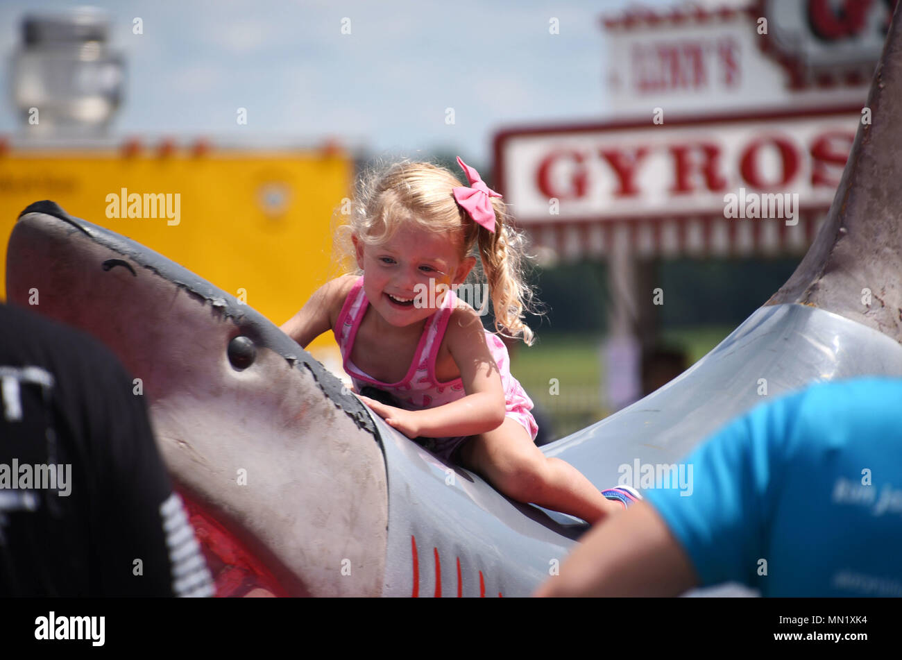 A little girl rides the mechanical shark ride during Family Day hosted ...