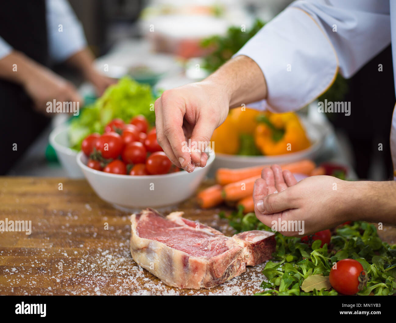 Master Chef hands putting salt on juicy slice of raw steak with ...