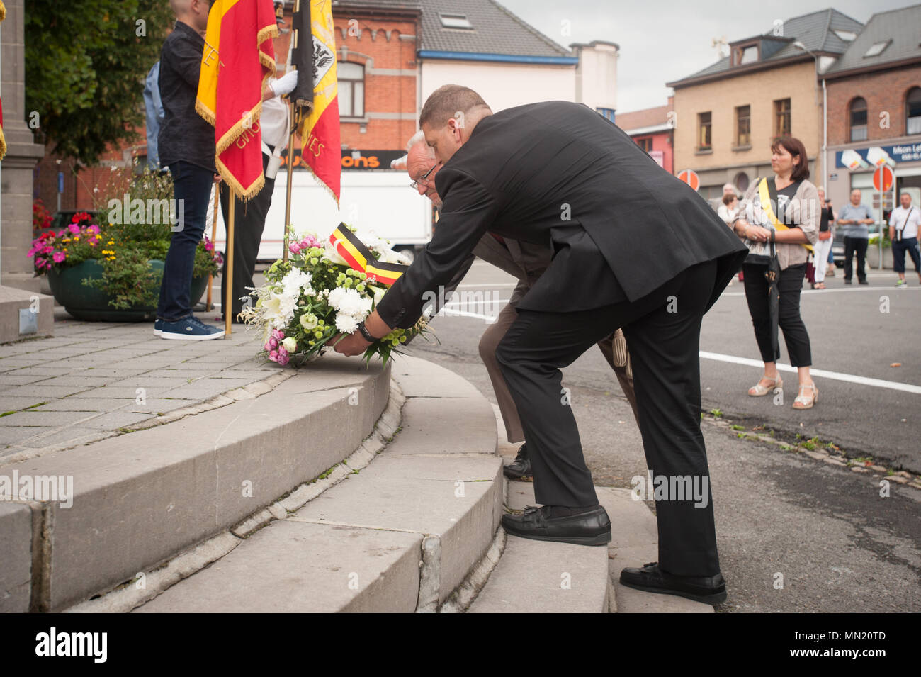 Belgian officials and U.S. service members lay flowers at a monument ...