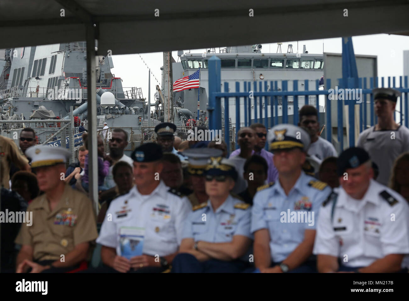 U.S. military personnel and guests are shown in front of the USS Barry ...