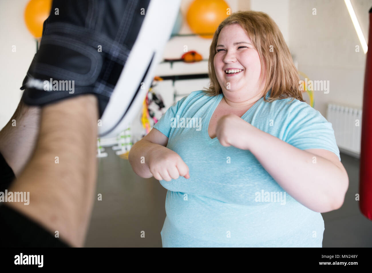 Waist up portrait of smiling obese woman working out in gym with ...