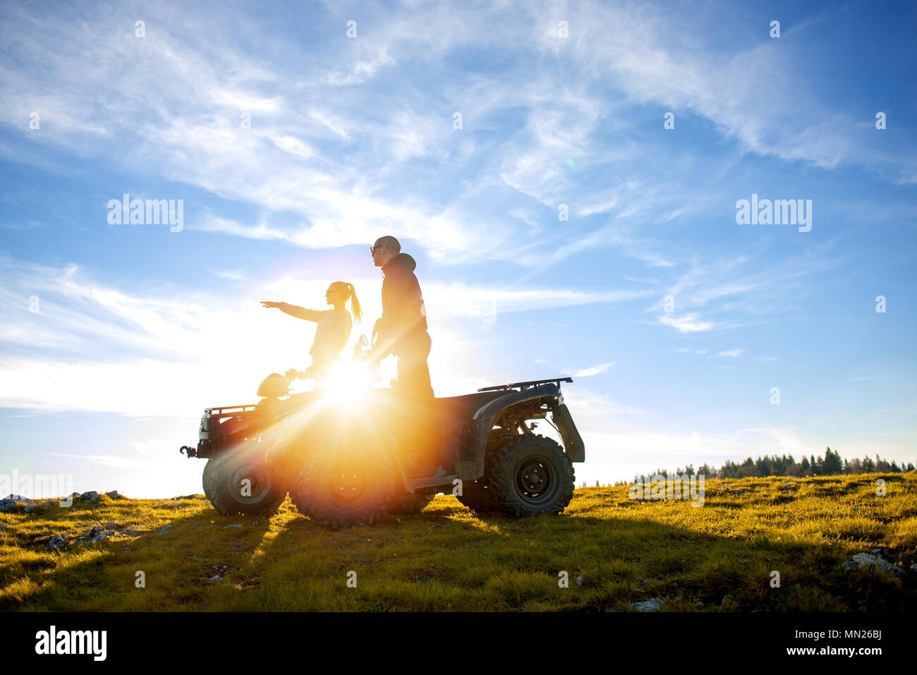 Beautiful couple is watching the sunset from the mountain sitting on ...