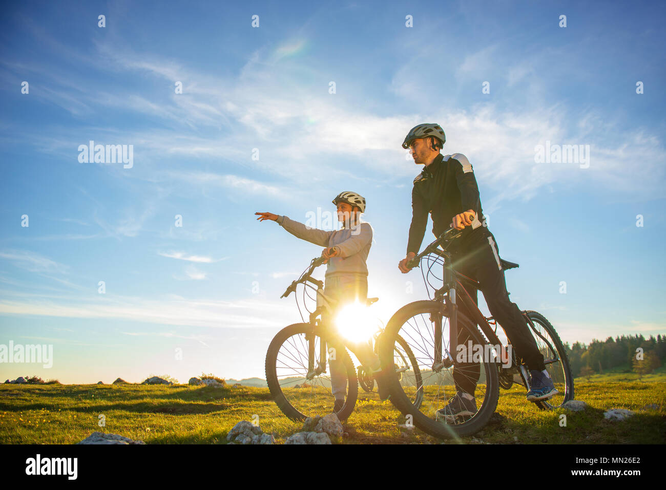 Biker couple with mountain bike pointing in distance at countryside ...