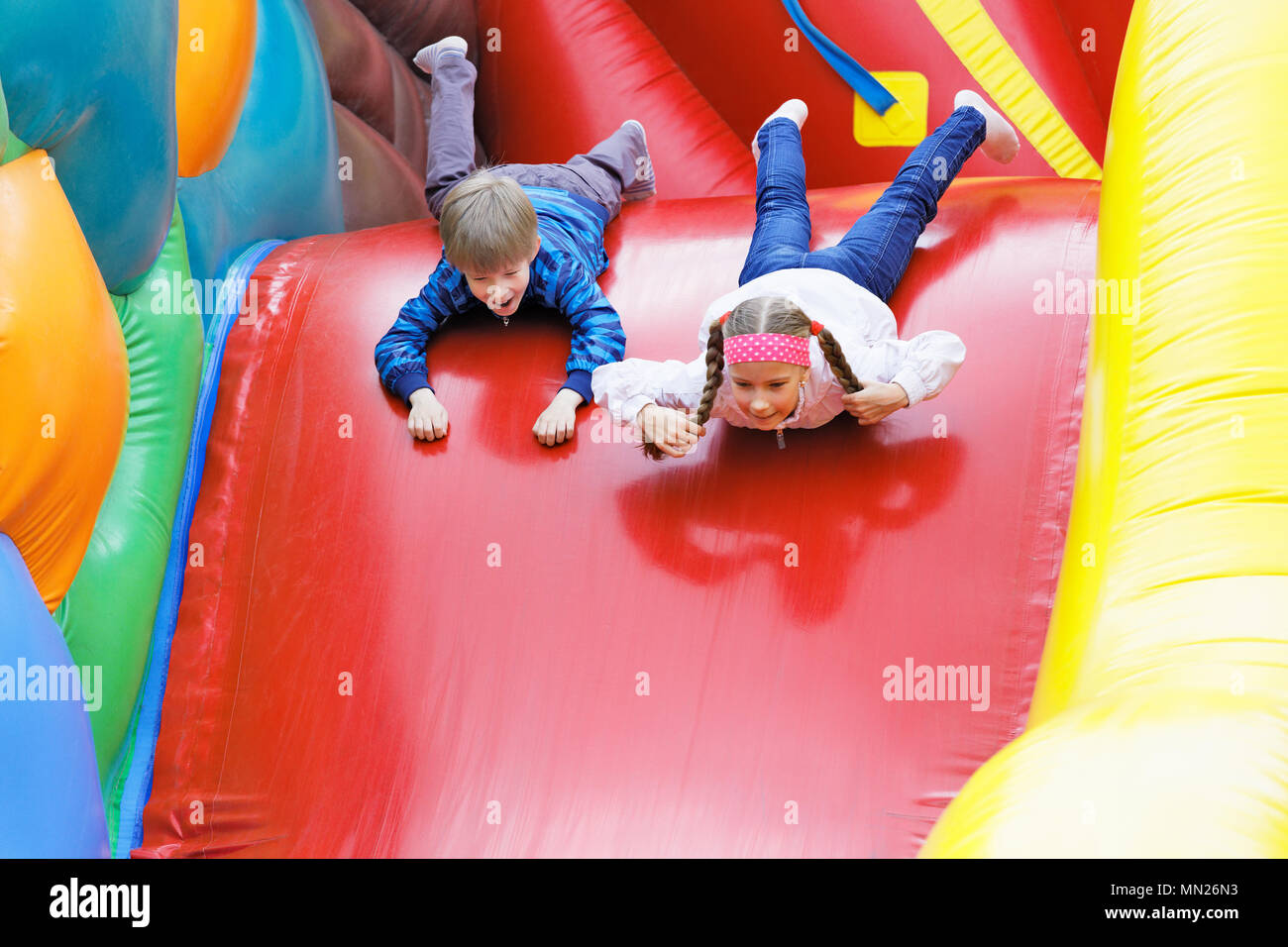Brother and sister have fun in the park on an inflatable attraction ...