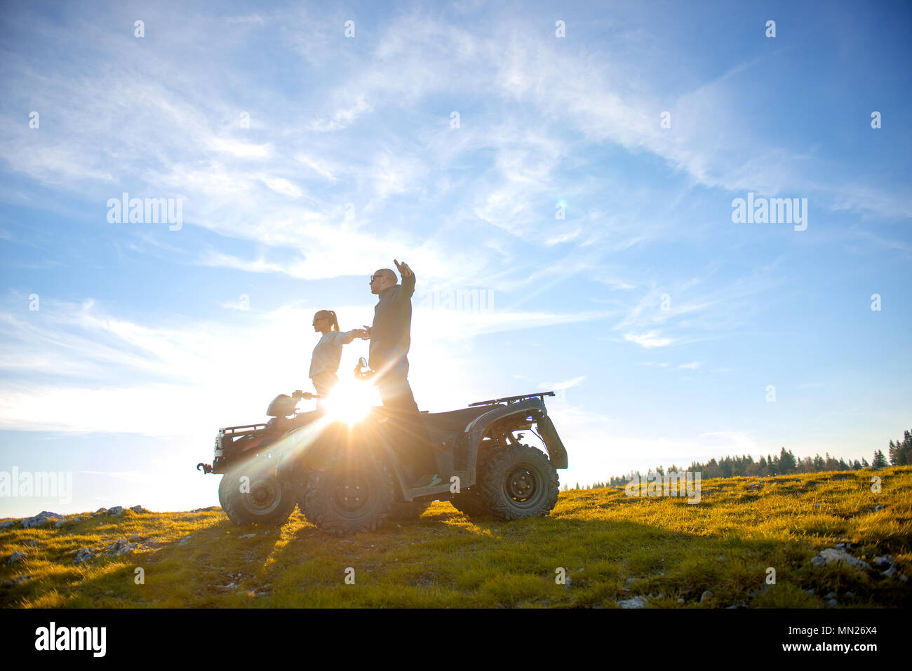 Beautiful couple is watching the sunset from the mountain sitting on ...