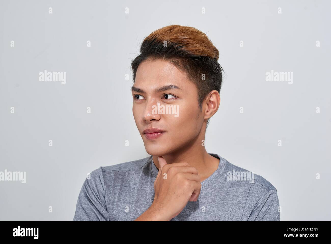 Handsome young smiling pensive man standing and looking up isolated on ...