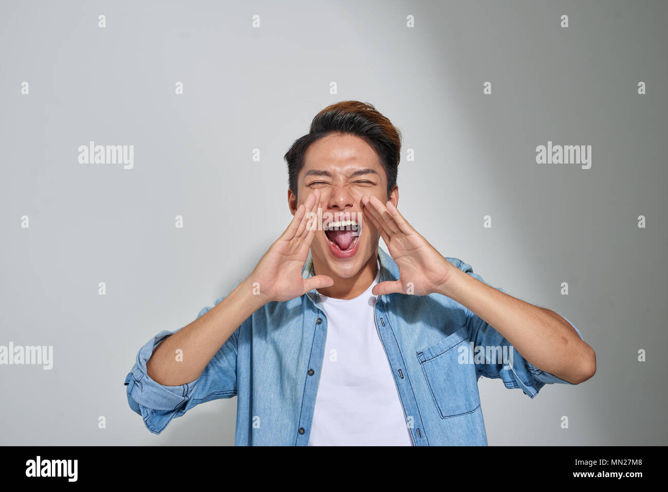 Young man shouting with hands cupped to his mouth Stock Photo - Alamy