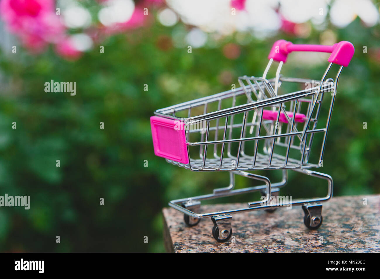 pink miniature shopping cart on blurred background of the garden Stock ...