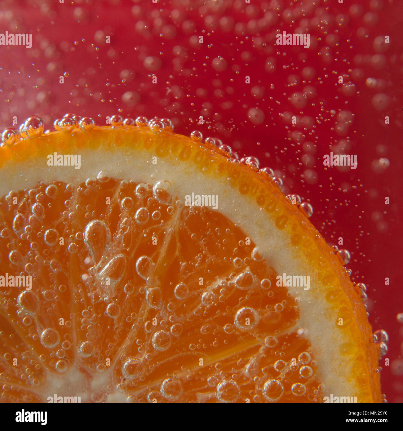 Orange slice in water with bubbles on red background, macro photo Stock ...