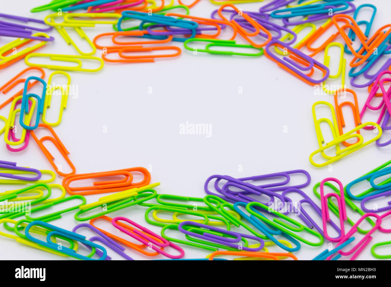A pile of brightly coloured paper clips on a white background Stock ...
