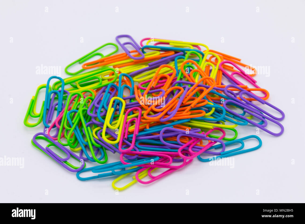A pile of brightly coloured paper clips on a white background Stock ...