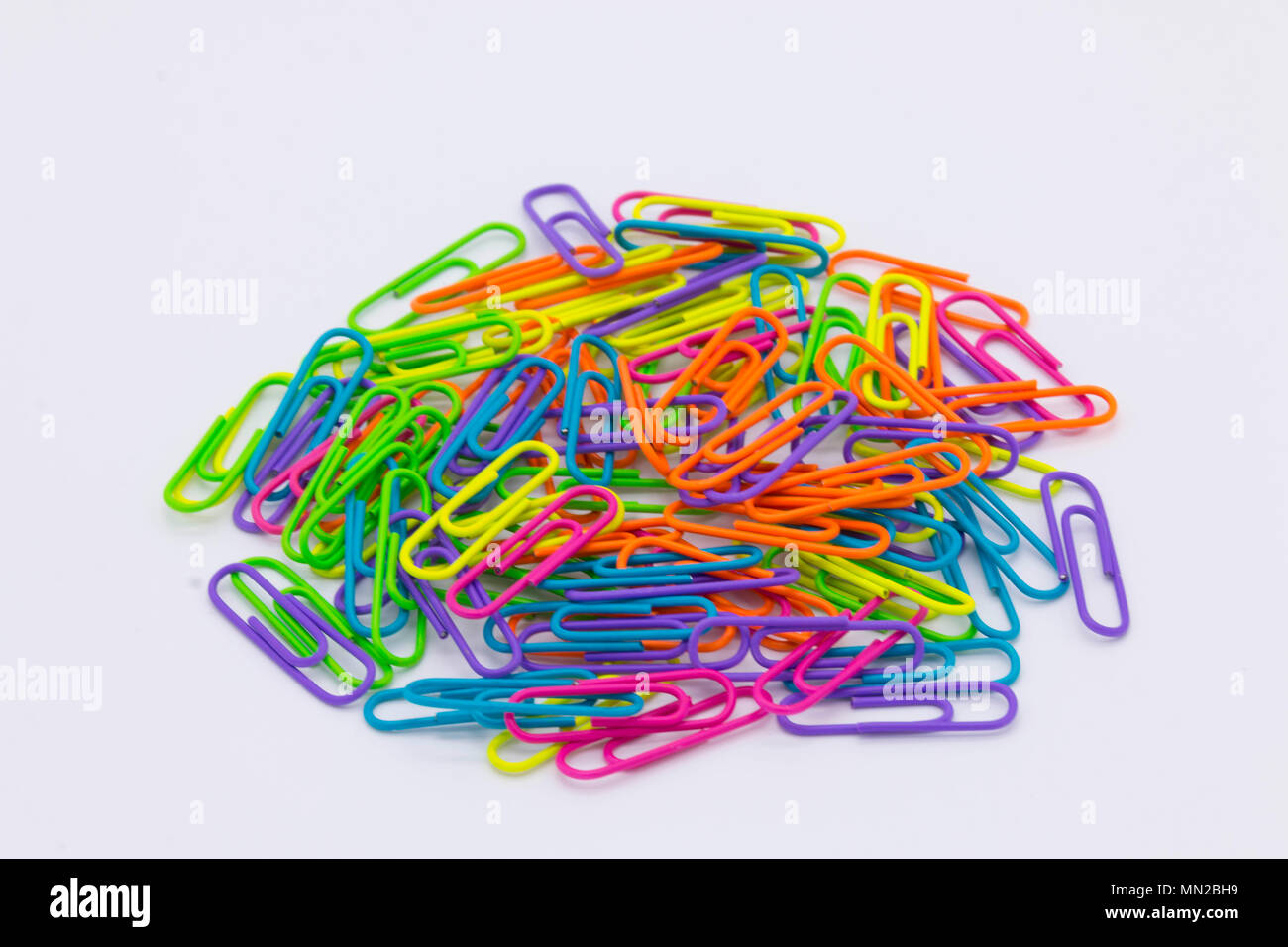 A pile of brightly coloured paper clips on a white background Stock ...