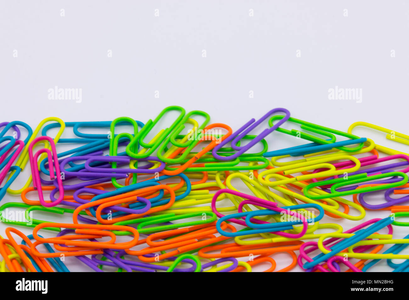 A pile of brightly coloured paper clips on a white background Stock ...