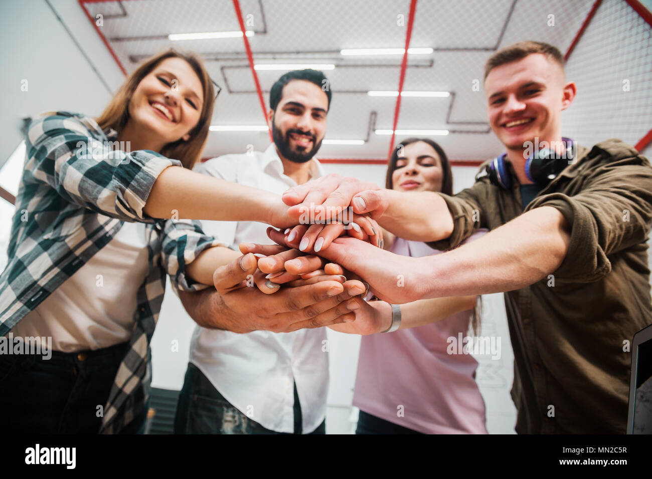 Young and motivated team of workers doing togetherness gesture ...