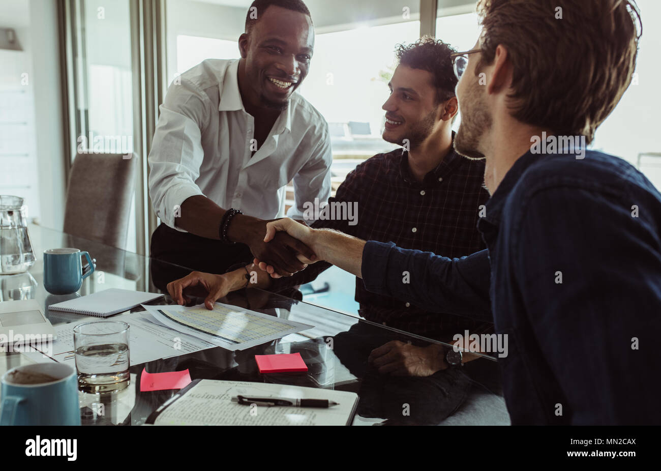 Businessmen discussing work sitting at conference table in office. Men ...