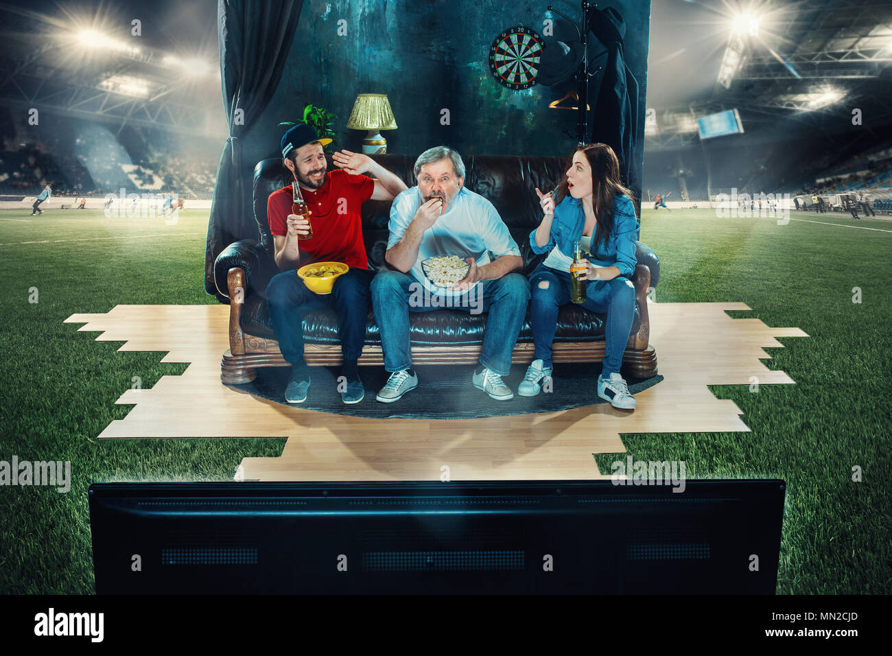 Ardent fans are sitting on the sofa and watching TV in the middle of a ...