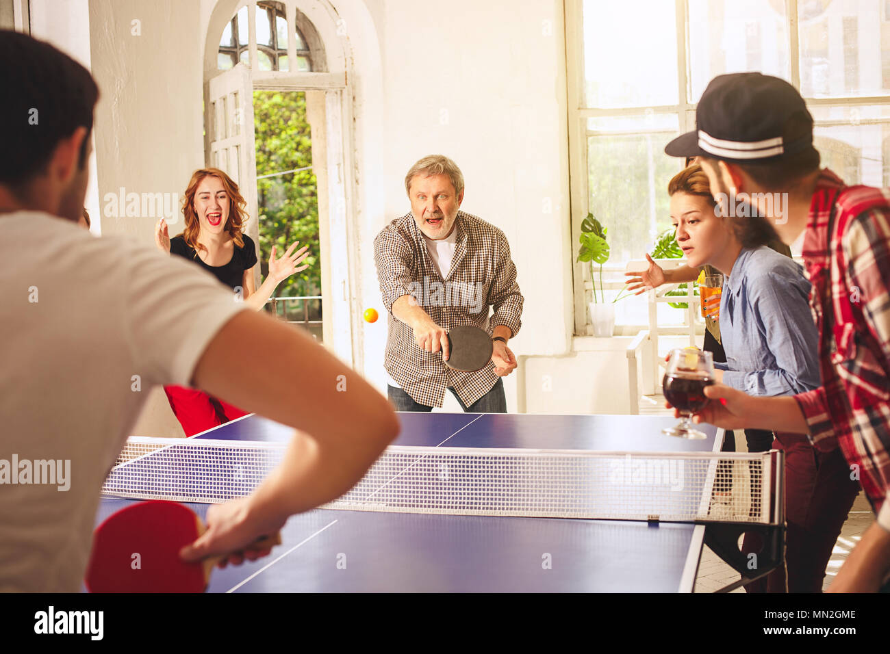 Group of happy young friends playing ping pong table tennis Stock Photo ...