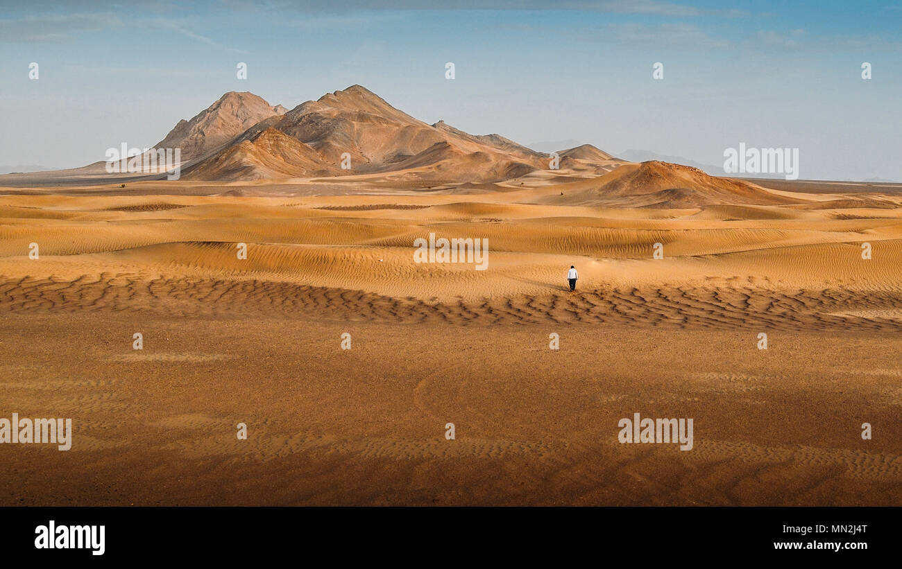 A man walking alone in the Dasht-e-Lut, a large salt desert located in ...