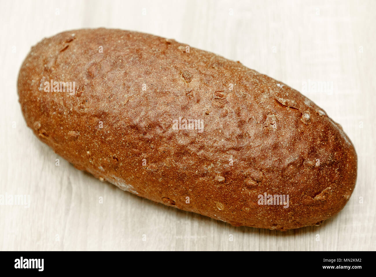 one black baked bread on a light wooden background Stock Photo - Alamy