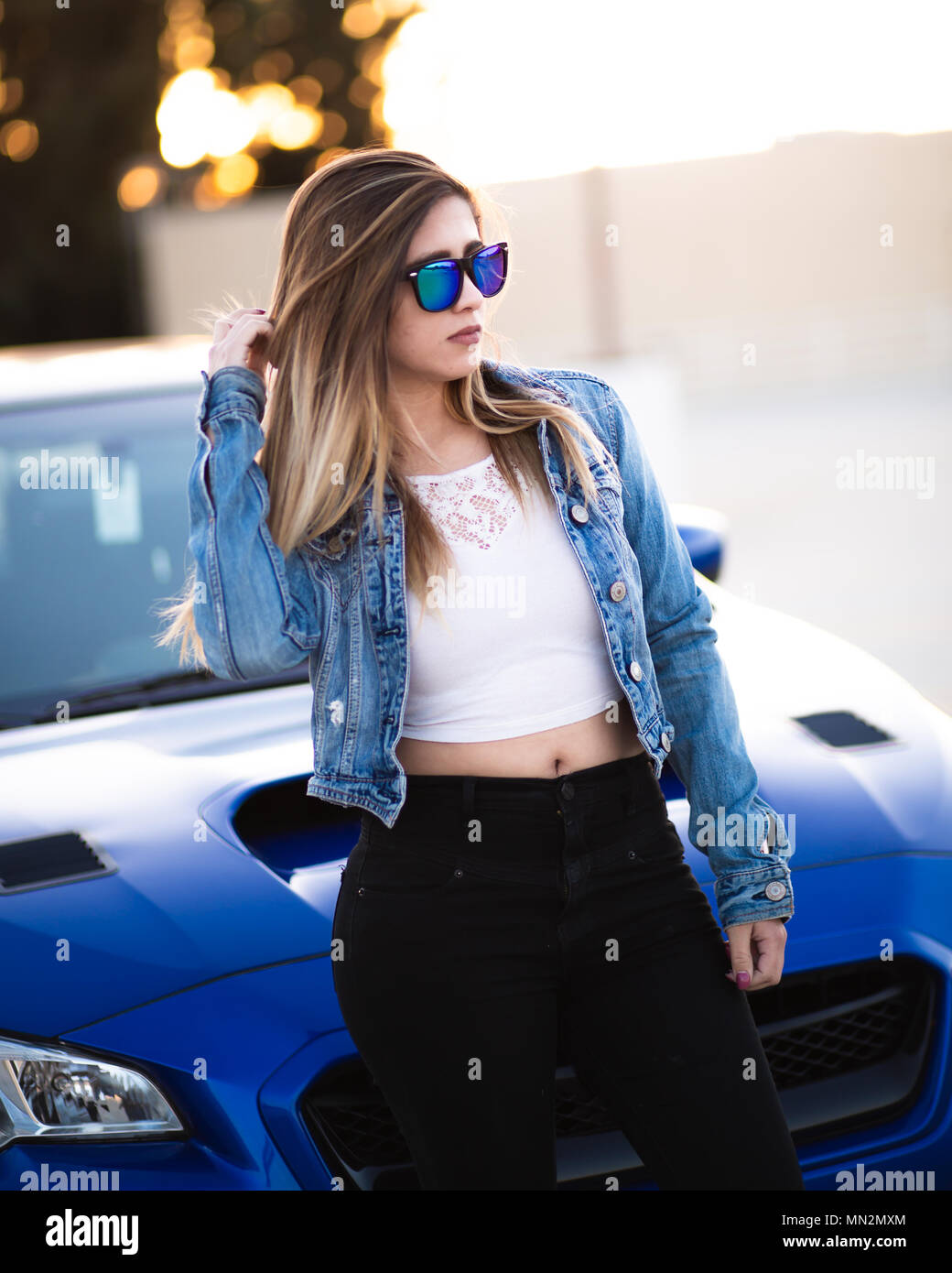 Young beautiful Latina with sunglasses enjoying the sunset with her car ...