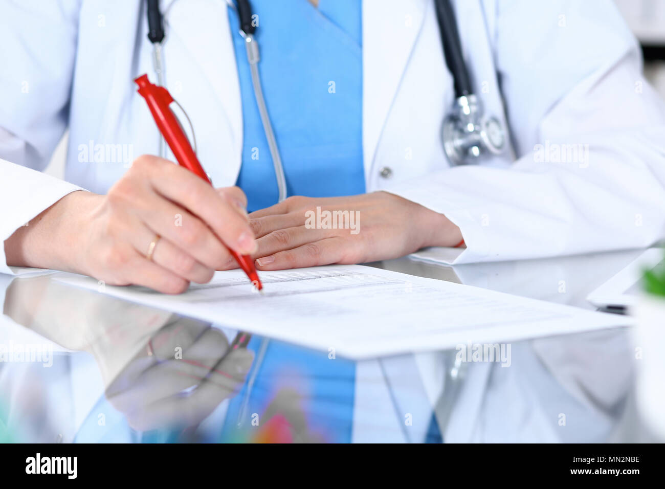 Female doctor filling up medical form by red pen, closeup. Physician ...