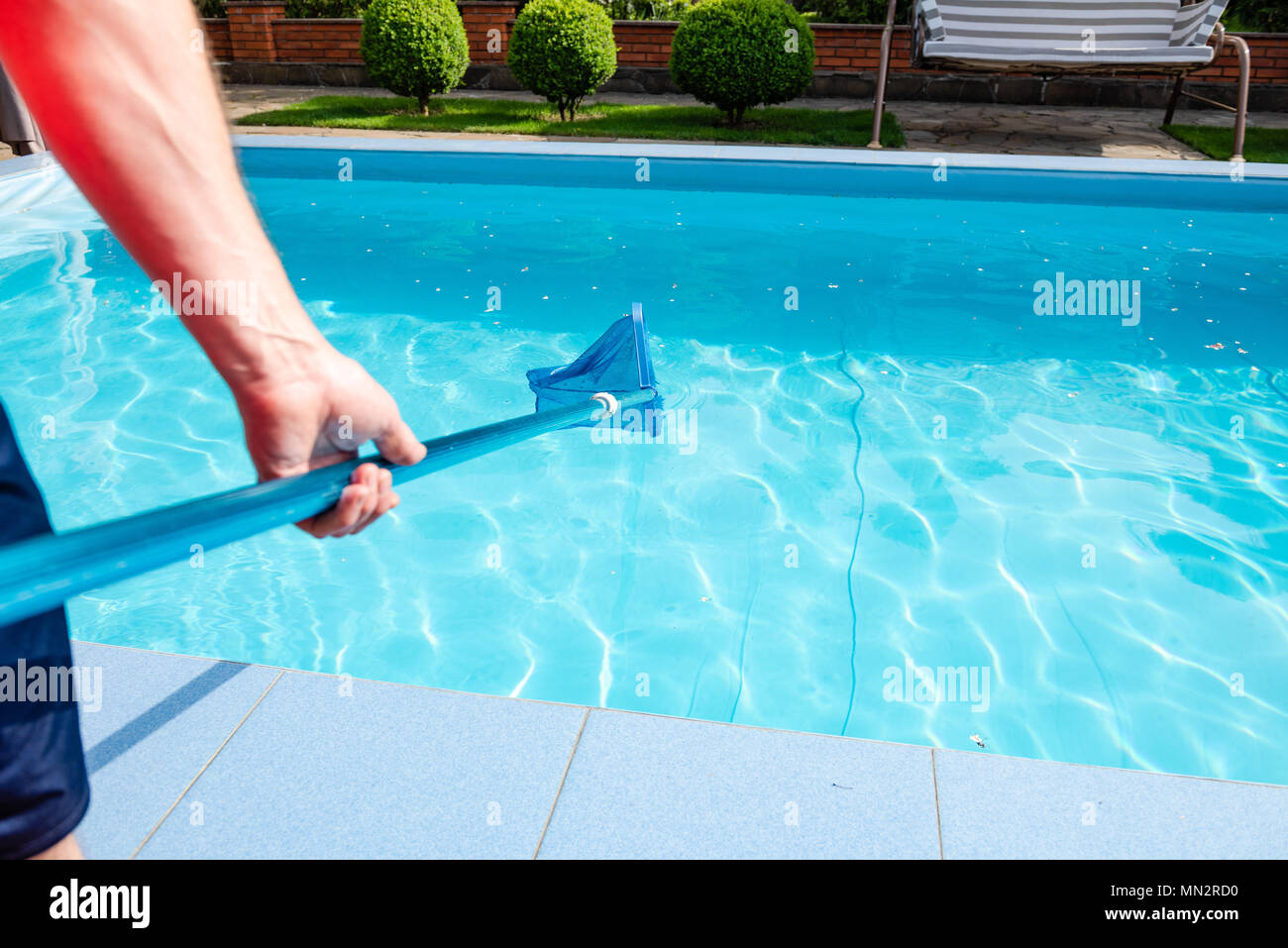Worker make maintenance of swimming pool. Male hand hold pool net ...