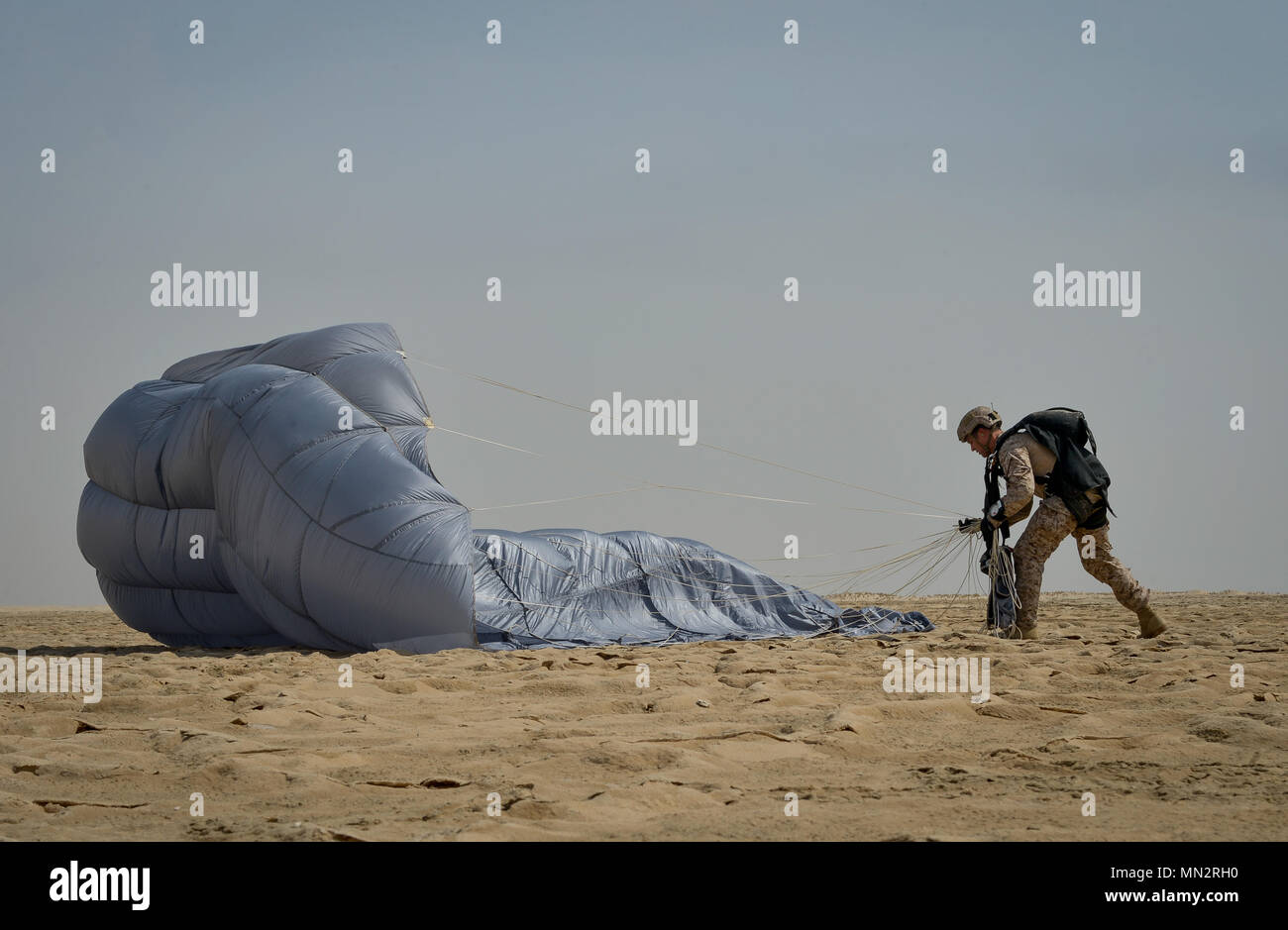A U.S. service member packs up his parachute after conducting a ...