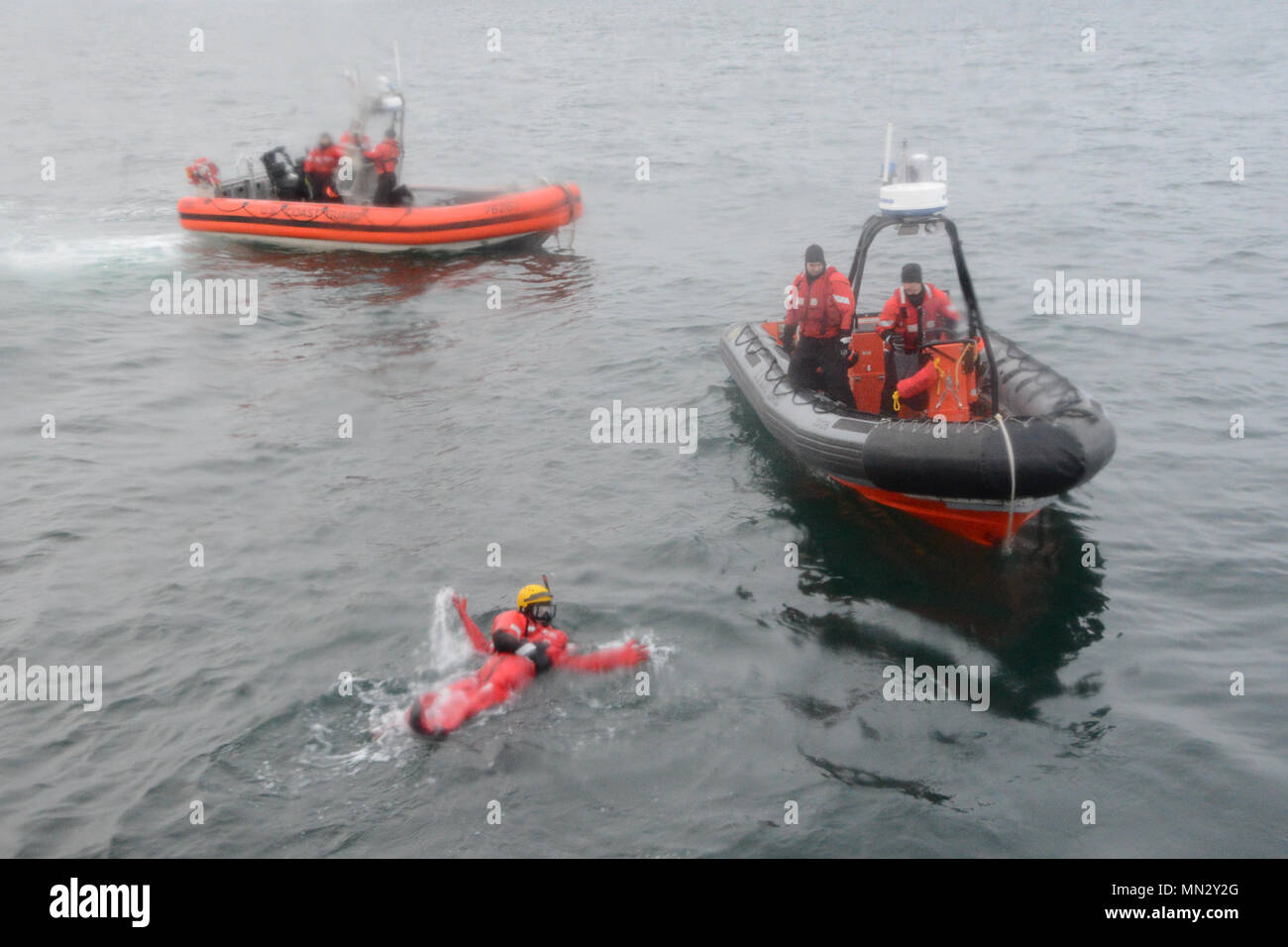 A cutter rescue swimmer assists a crewmember from the Coast Guard ...
