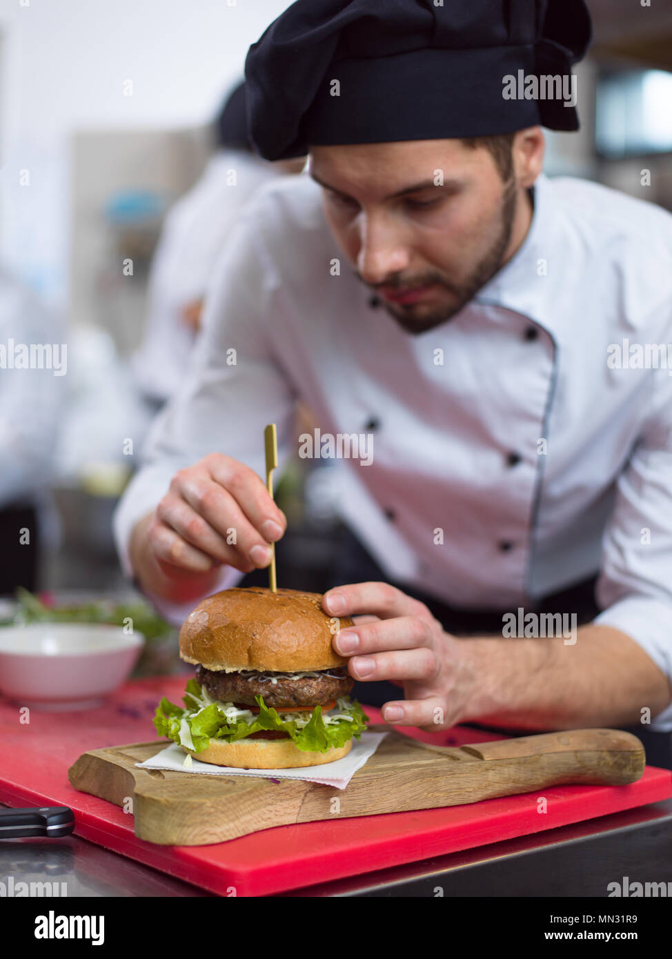 master chef putting toothpick on a burger in restaurant kitchen Stock ...