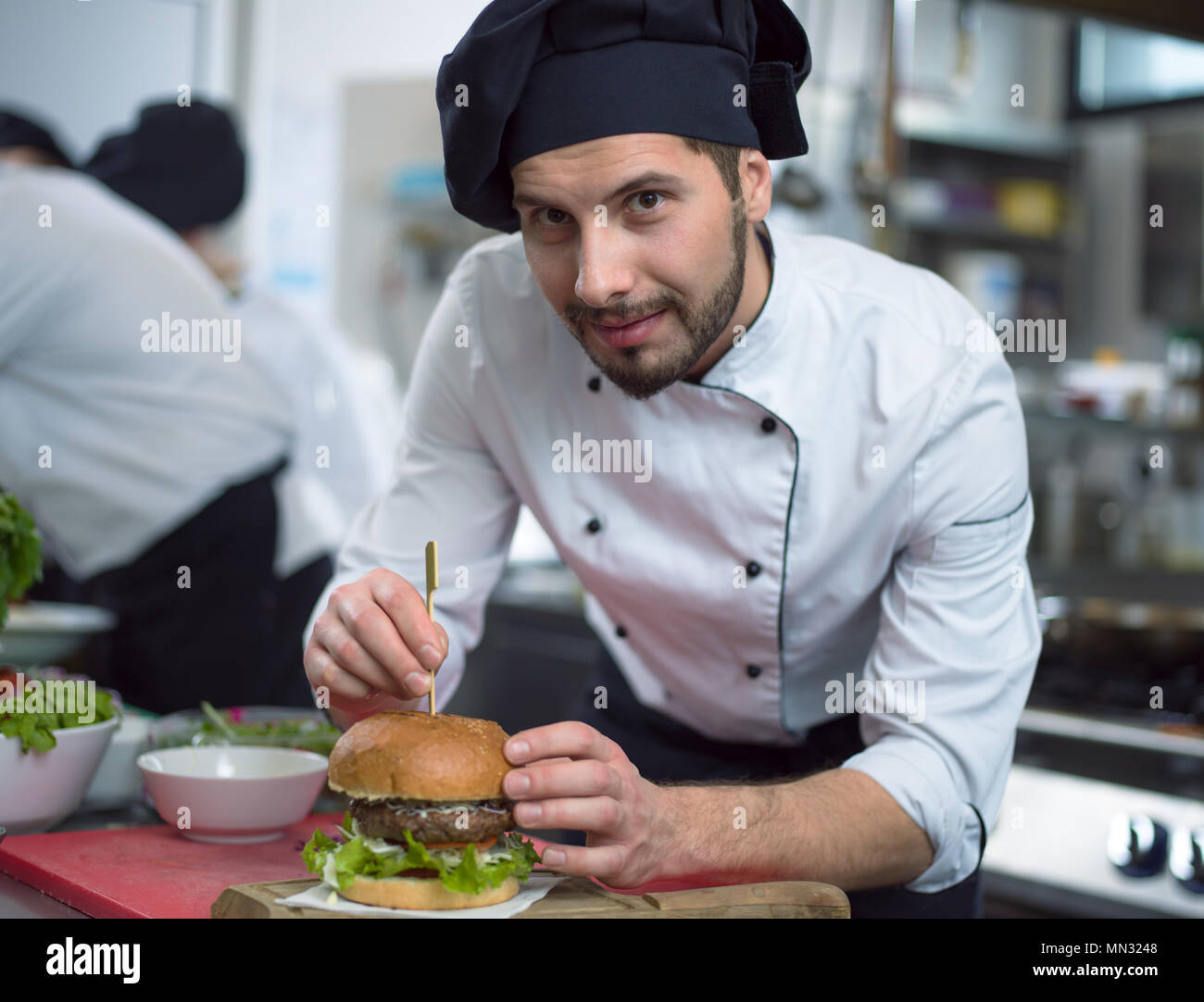 master chef putting toothpick on a burger in restaurant kitchen Stock ...