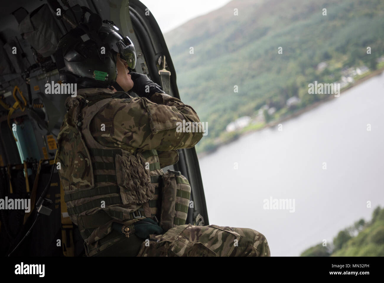 A Royal Marine Aircrewnan looks out the side of a Merlin Mk2 Helicopter ...