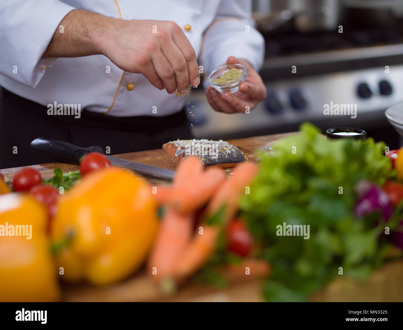 Chef hands preparing marinated Salmon fish fillet for frying in a ...
