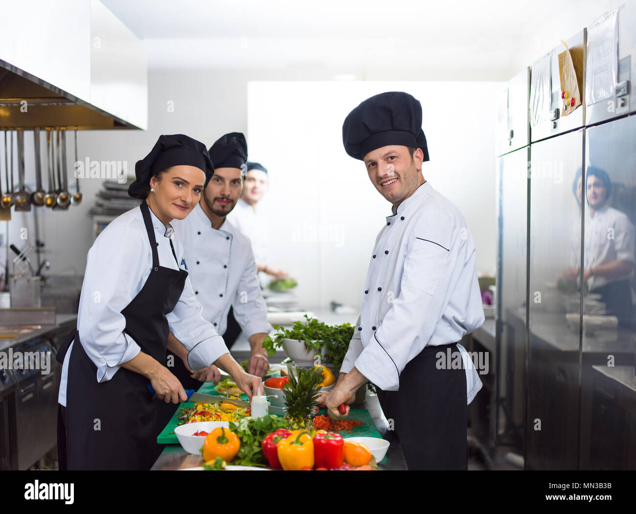 Professional team cooks and chefs preparing meals at busy hotel or ...