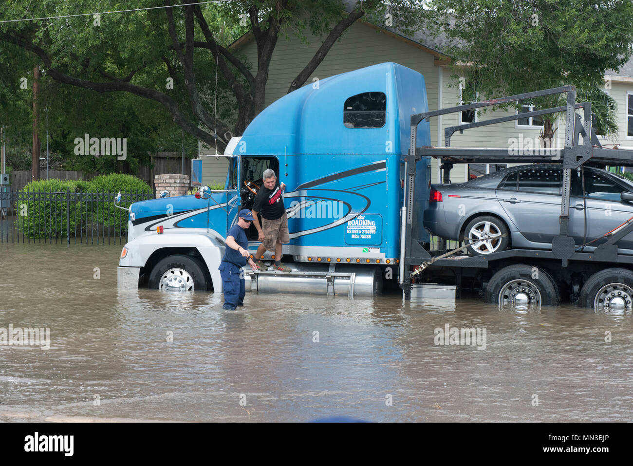 A Coast Guard flood punt team member assists a truck driver in a ...