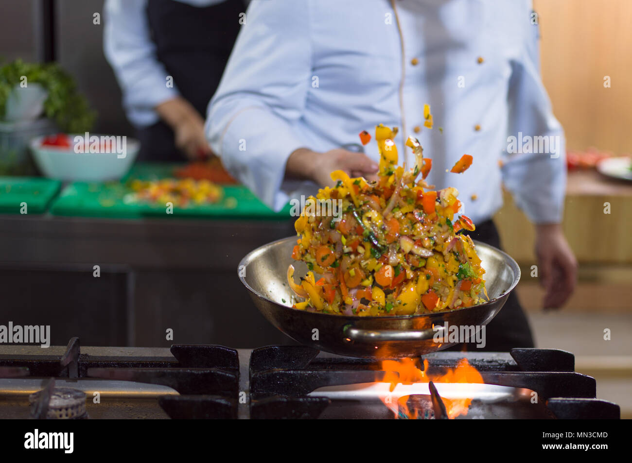 Young male chef flipping vegetables in wok at commercial kitchen Stock ...