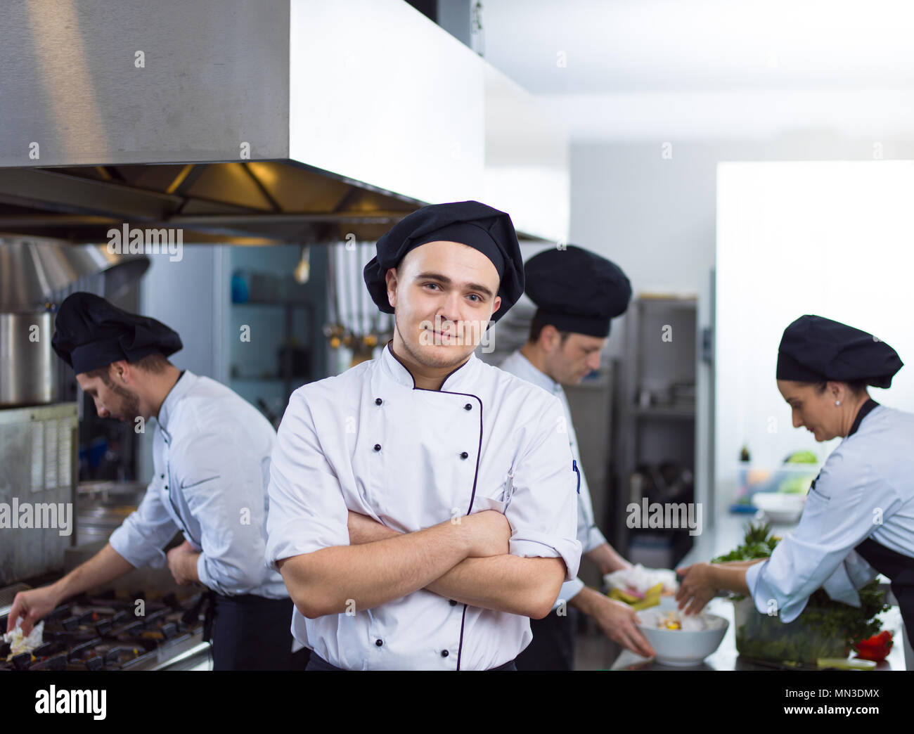 Portrait of young chef standing in commercial kitchen at restaurant ...