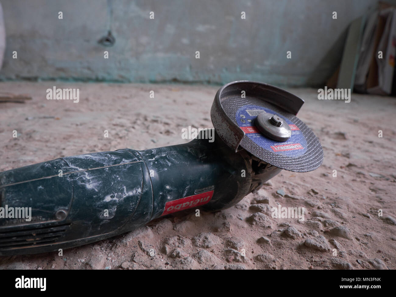 Side grinder on a floor in front of a dirty wall. Overhaul concept ...