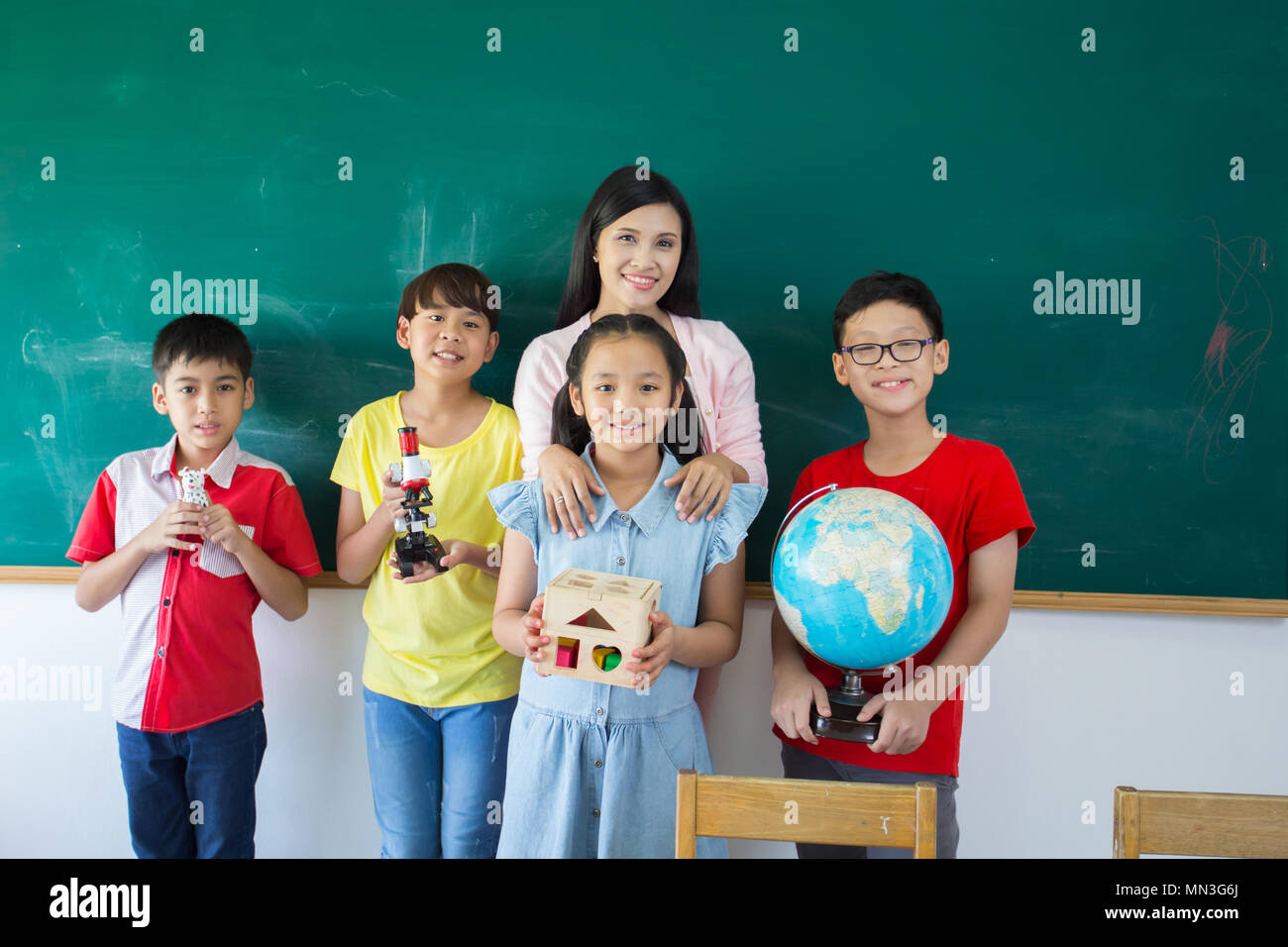 Group of Asian students with woman teacher standing on chalkboard and ...