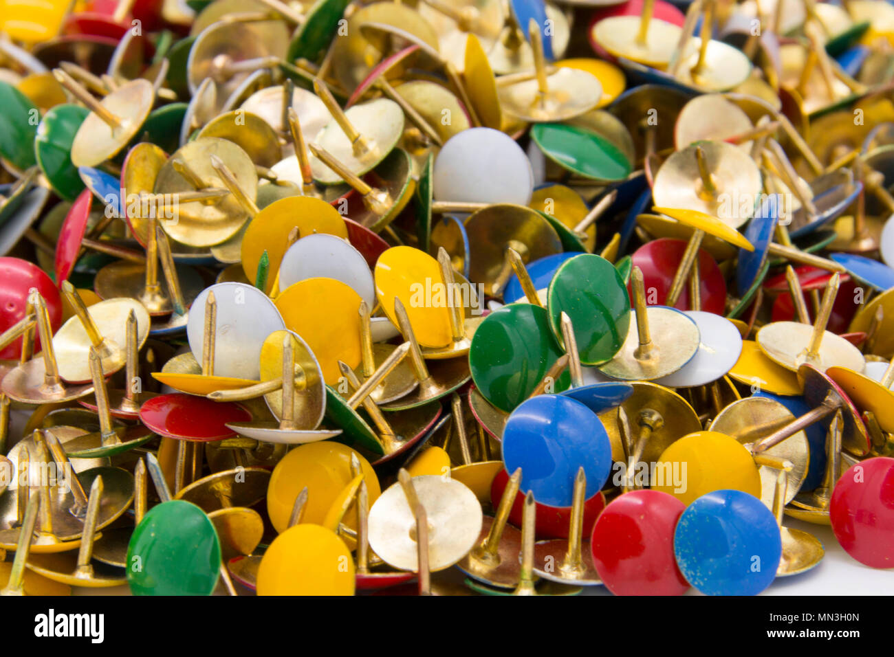 Pile of colourful drawing pins / thumb tacks on a white background ...