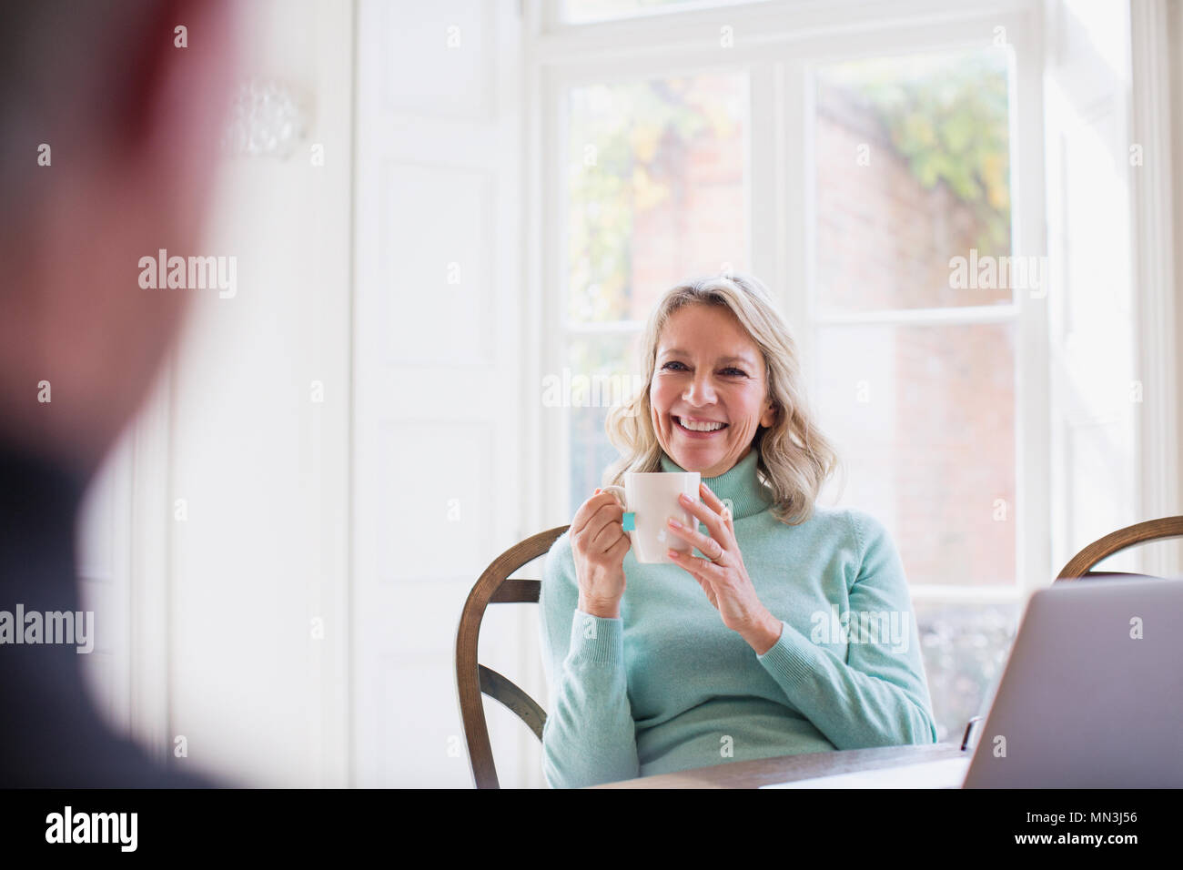 Smiling mature woman drinking tea, talking to man Stock Photo - Alamy