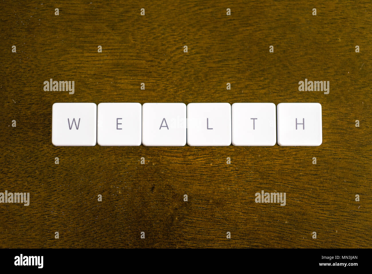 WEALTH word written on plastic keyboard alphabet with dark background ...