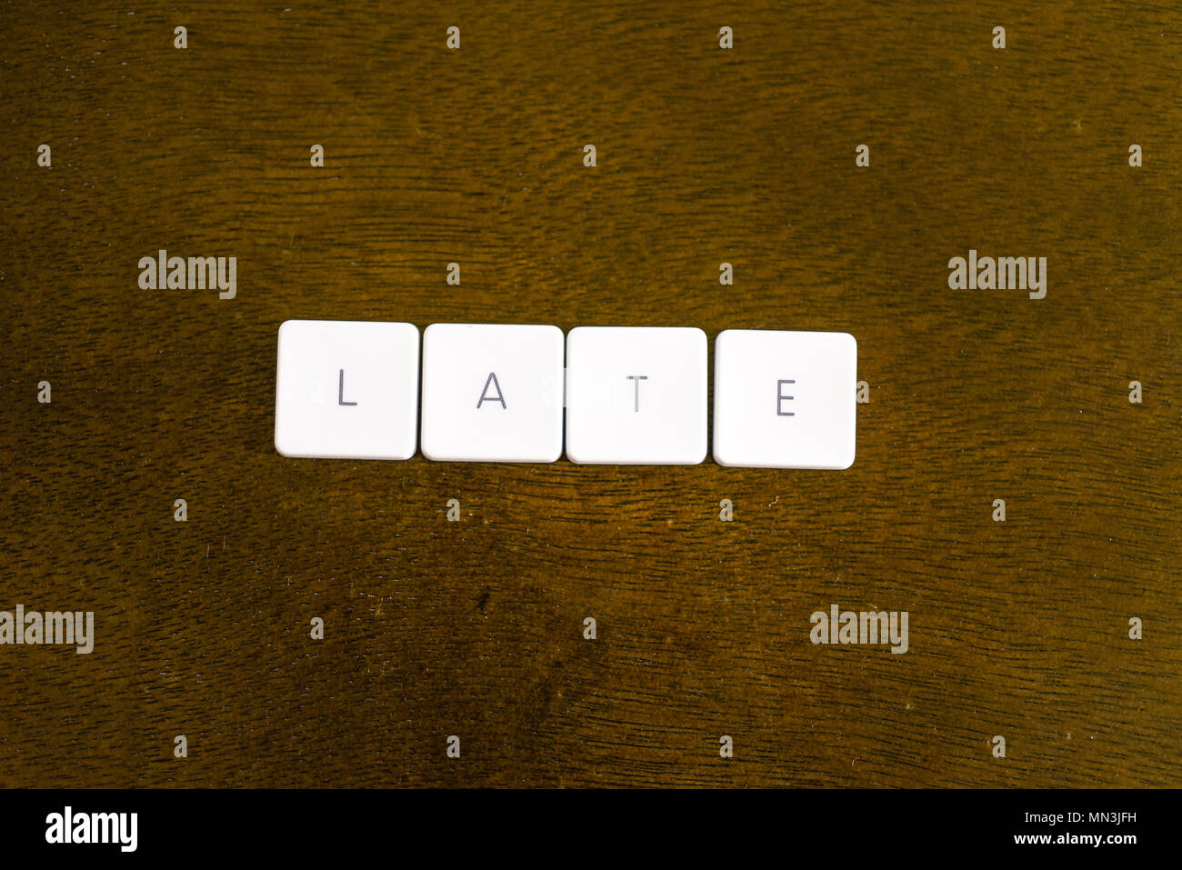 LATE word written on plastic keyboard alphabet with dark background ...