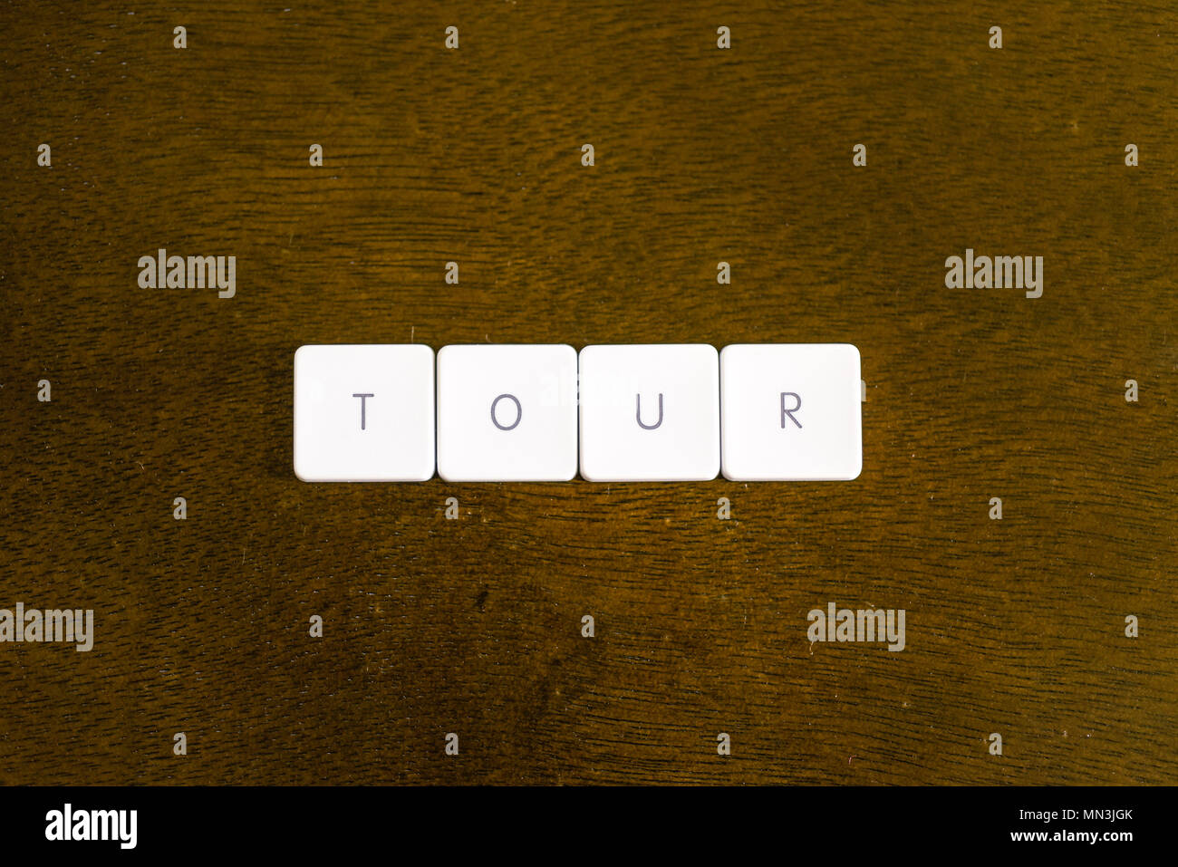 TOUR word written on plastic keyboard alphabet with dark background ...