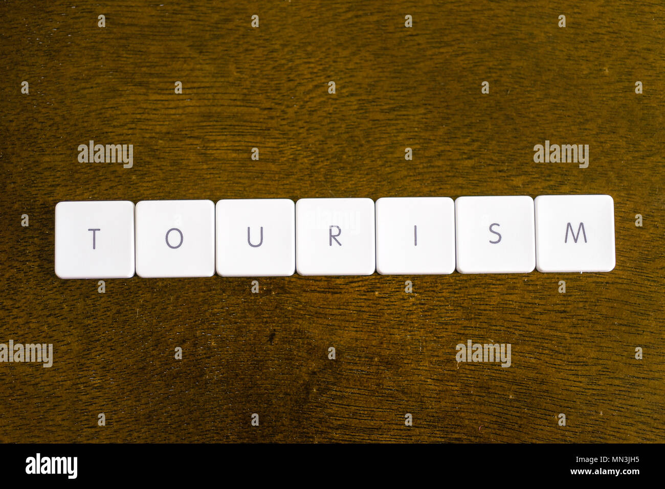 TOURISM word written on plastic keyboard alphabet with dark background ...