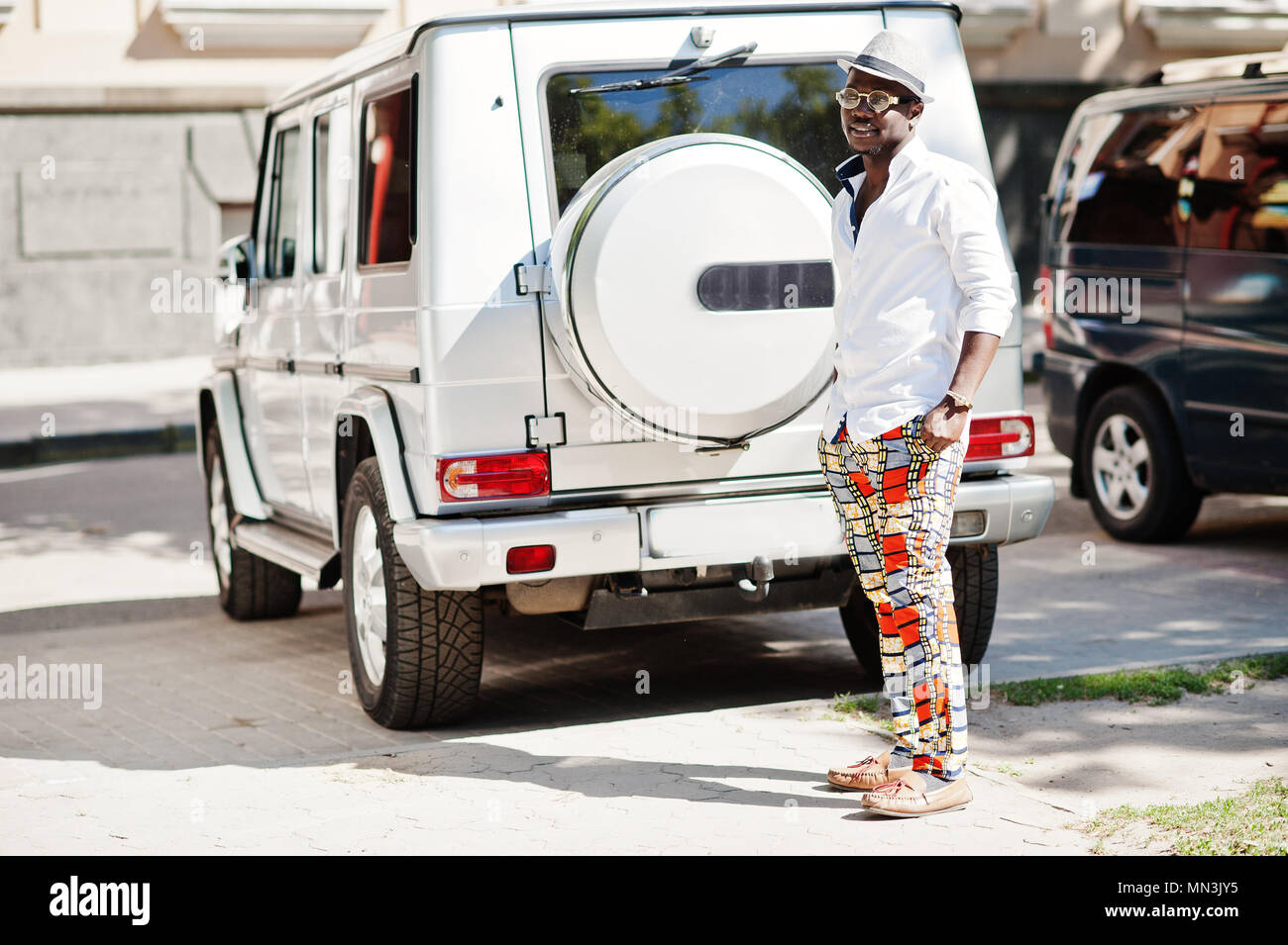 Stylish african american man in white shirt and colored pants with hat ...