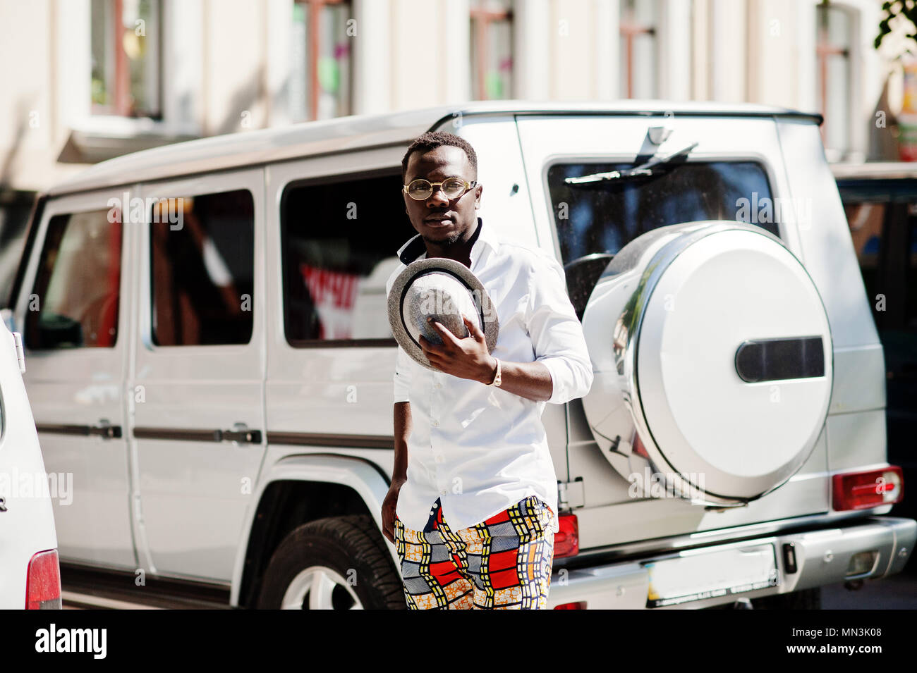 Stylish african american man in white shirt and colored pants with hat ...