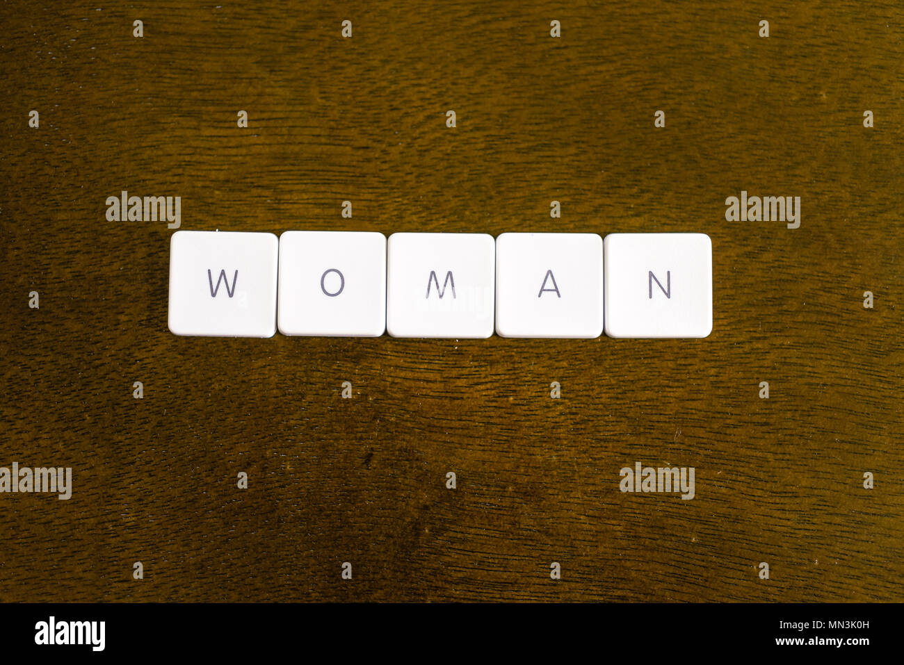 WOMAN word written on plastic keyboard alphabet with dark background ...