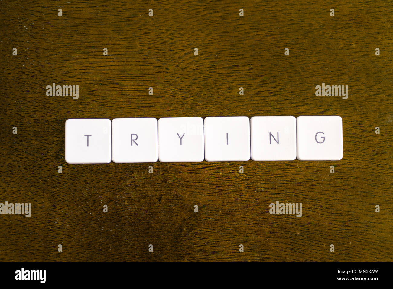 TRYING word written on plastic keyboard alphabet with dark background ...