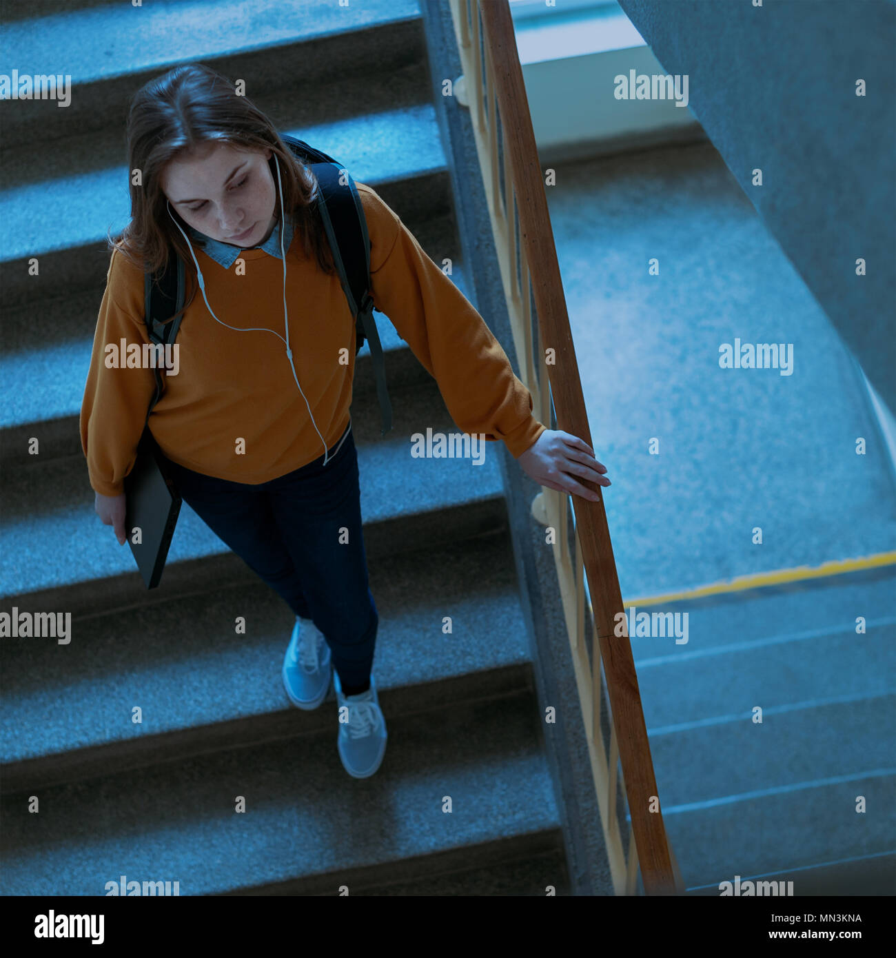 Young depressed lonely female college student walking down the stairs ...