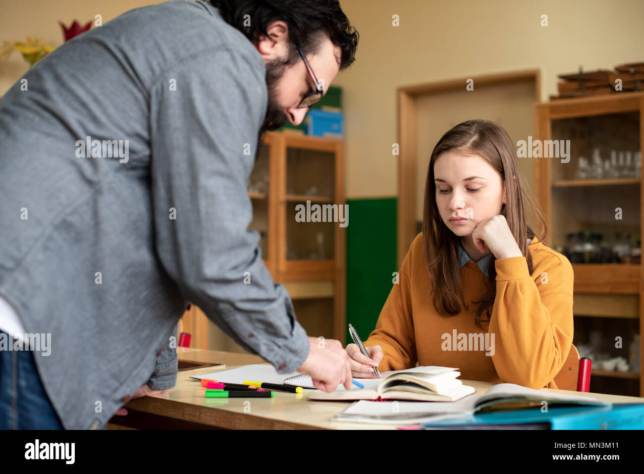 Young male hispanic teacher helping his student in chemistry class ...